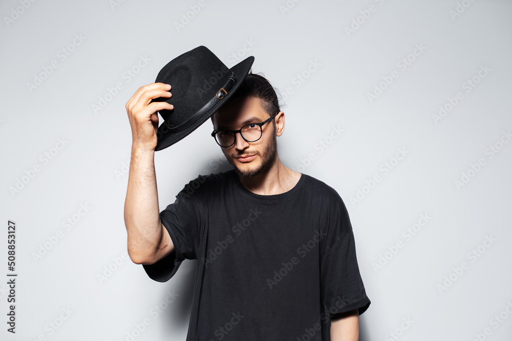Studio portrait of young man taking off the hat from head on white ...