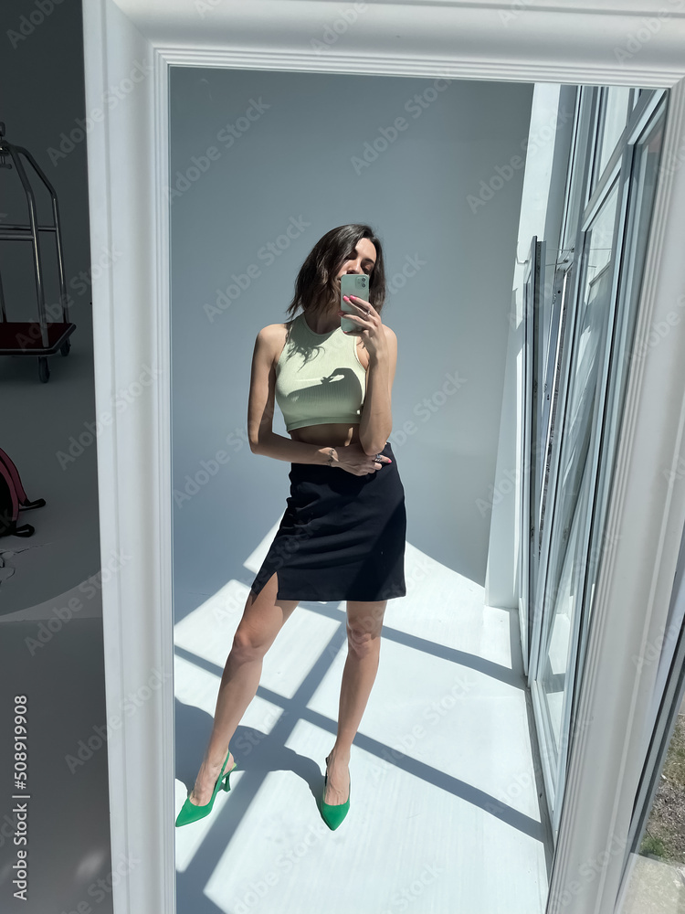 Fit tanned woman in classic short black skirt, light green crop top and ...