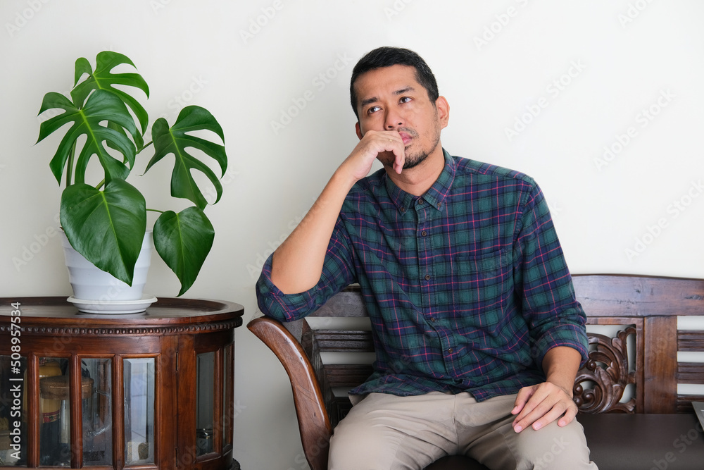 Adult Asian man thinking about something with sad expression when ...
