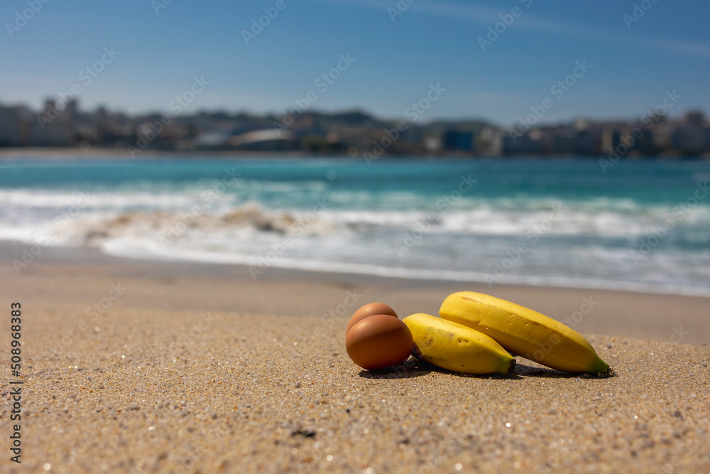 Breakfast by the ocean. Bananas and eggs on the sand by the ocean ...