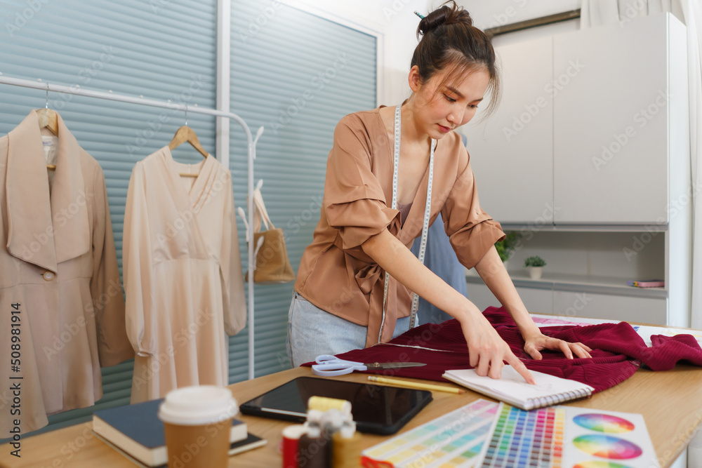 Fashion design concept, Asian female tailor pointing on dress drawing ...