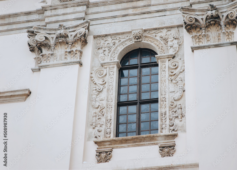 An antique baroque window with a lattice frame and decorative stucco on ...