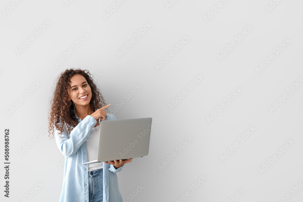 Beautiful African-American woman with laptop pointing at something on ...