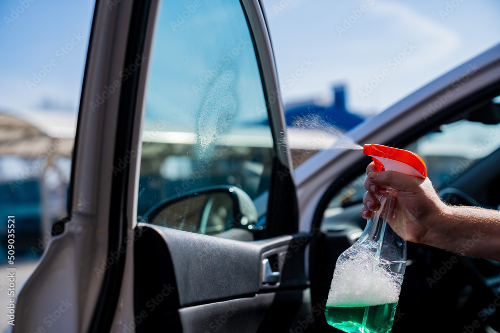 self-service car wash. a man washes the car window with glass cleaning ...