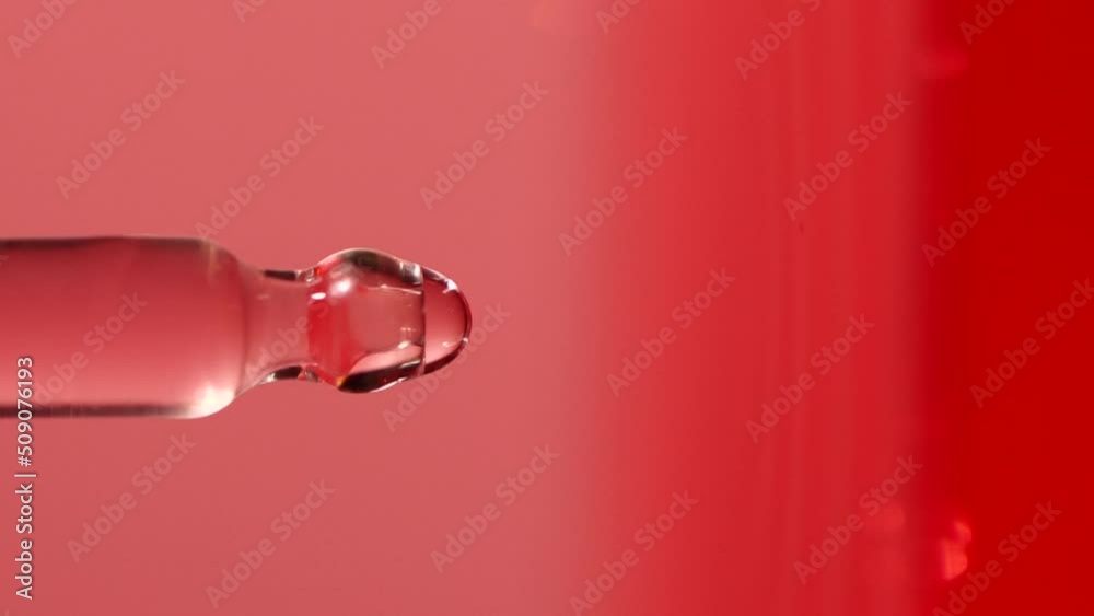 Slow motion of pink serum fluid, oil drop falling from dropper, pipette ...