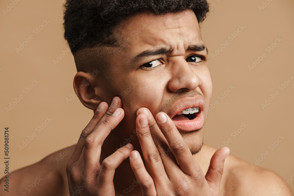 Photo & Art Print Young shirtless man frowning while squeezing pimple ...