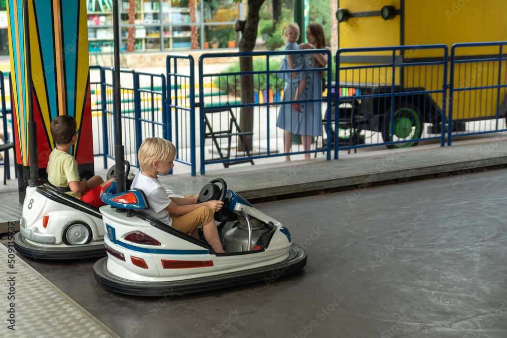 Children driving bumper car in the amusement park. Young drivers having ...