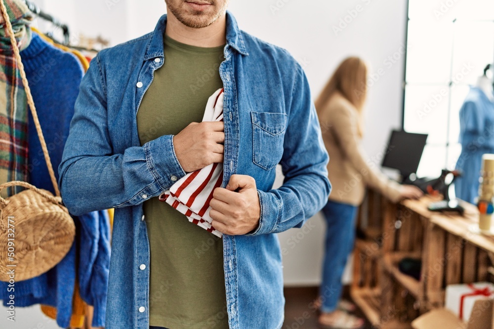 Young hispanic robber man stealing shirt at clothes store. Stock Photo ...