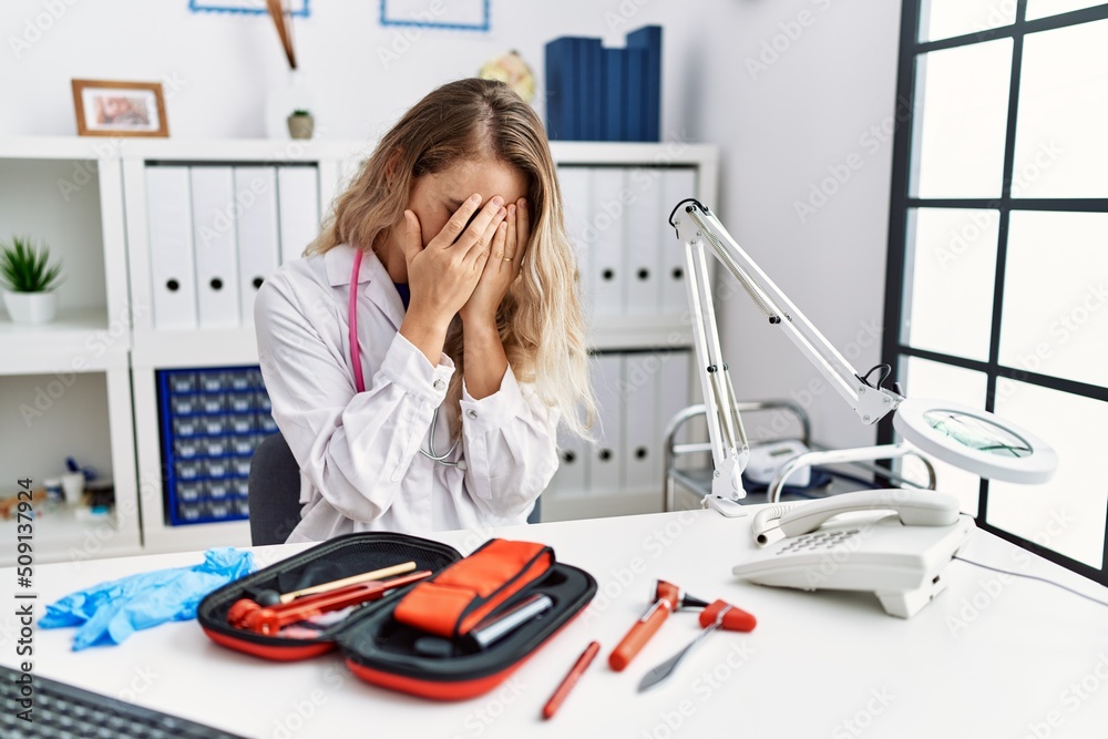 Young beautiful doctor woman with reflex hammer and medical instruments ...