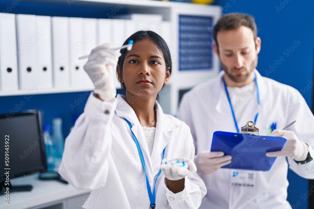 Man and woman scientists holding capsule writing report at laboratory ...