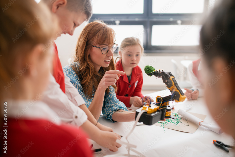Group of kids with young science teacher programming electric toys and ...