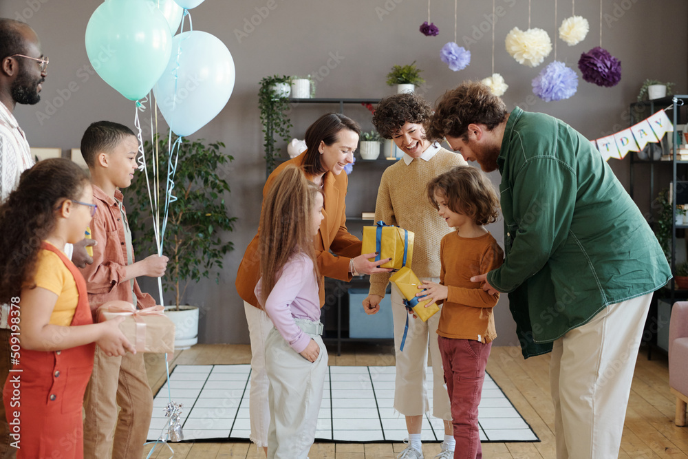 Little boy taking presents from his friends during birthday, they ...