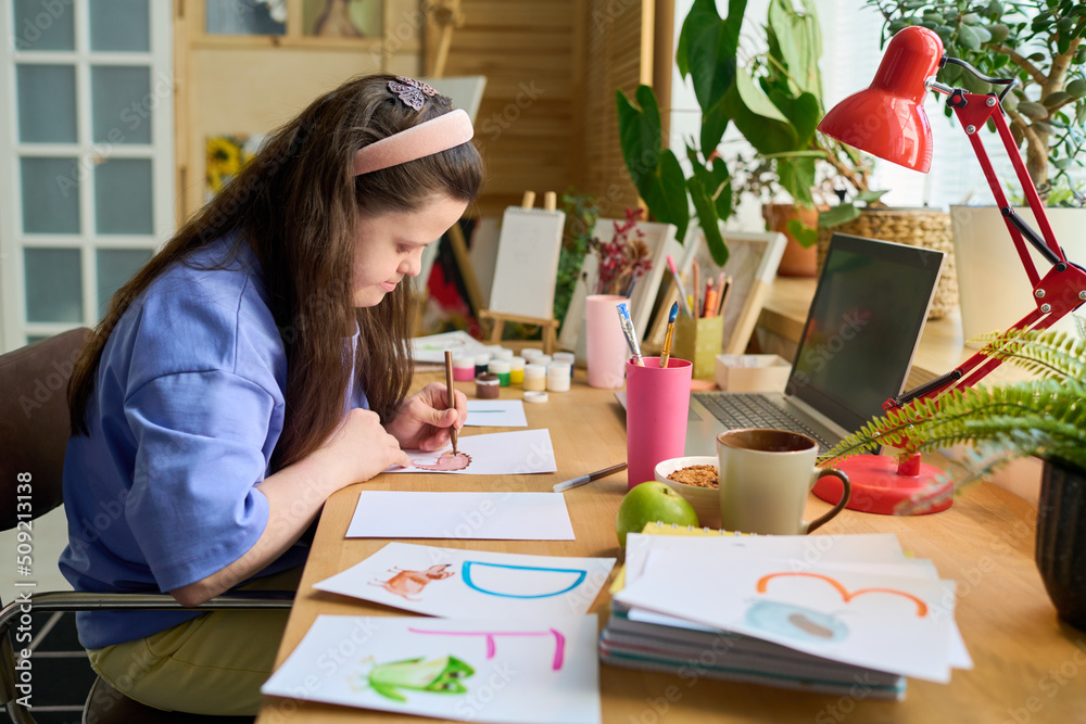 Young female with Down syndrome drawing letters of alphabet and small ...