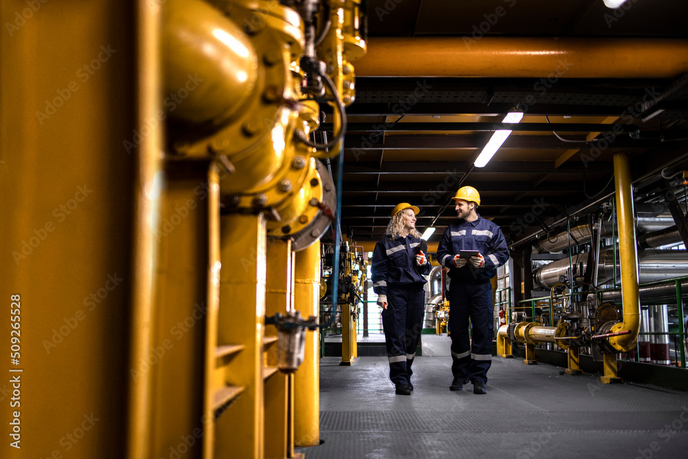 Industrial engineers walking by gas pipeline inside refinery and ...