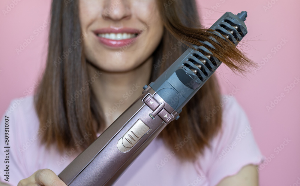 young woman using a modern straightener head on hair styler.smiling ...