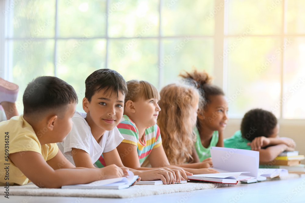 Cute little children reading books on floor in classroom Stock Photo ...