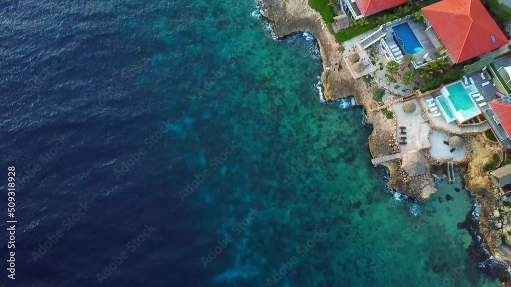 Overhead dolly-in aerial view of mansions on the shore of Jan Thiel ...