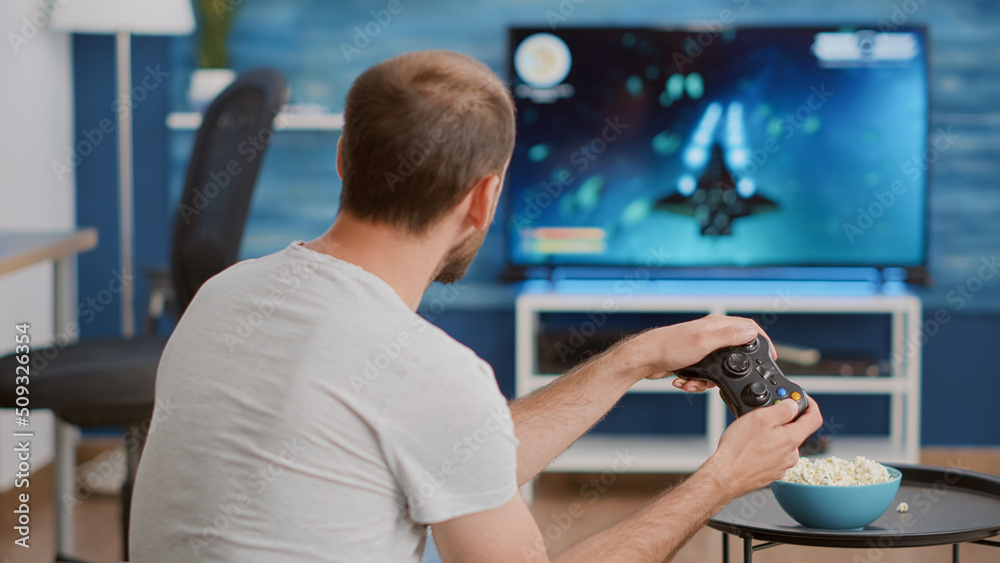 Man holding wireless controller playing console video game on tv while ...