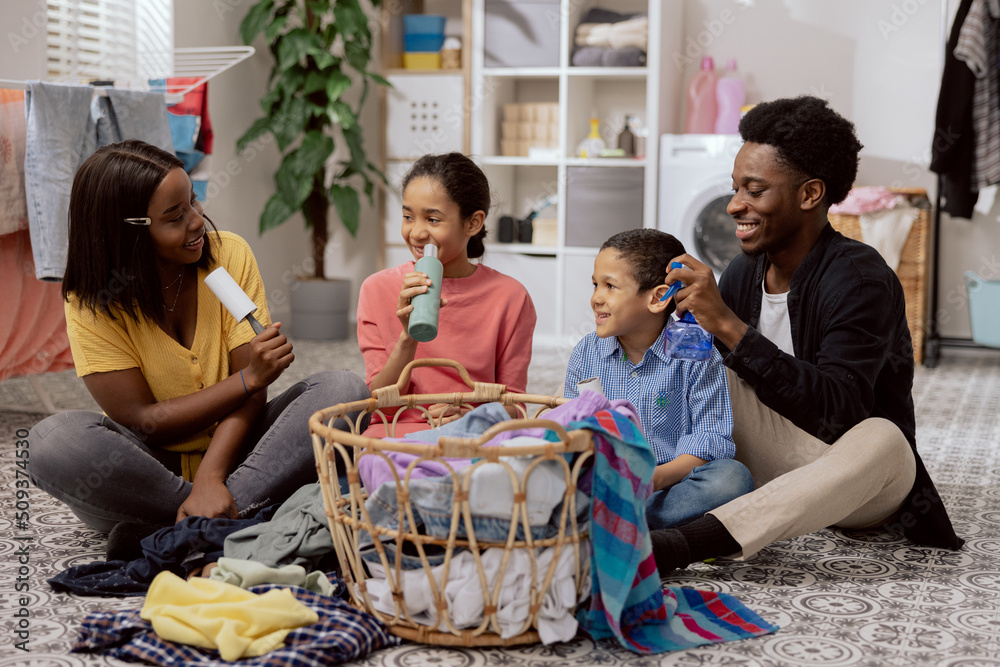 A family sits on the laundry room floor sorting clothes before putting ...