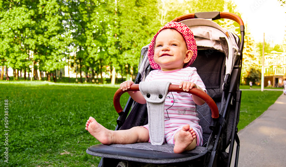 funny baby in a hat in a stroller outdoors in a green summer park Stock ...