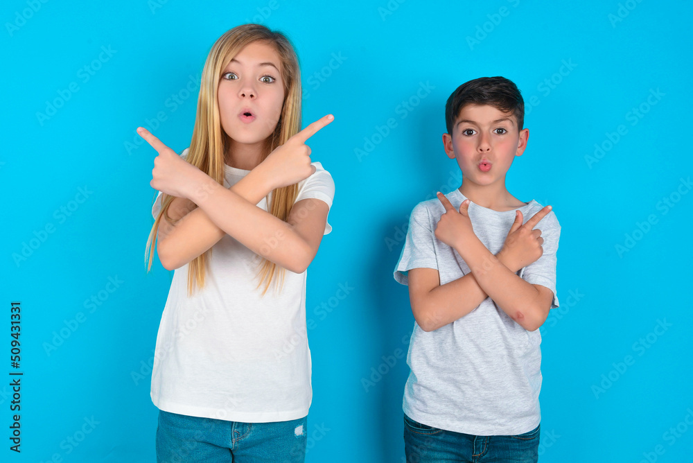 Confused two kids boy and girl standing over blue studio background ...