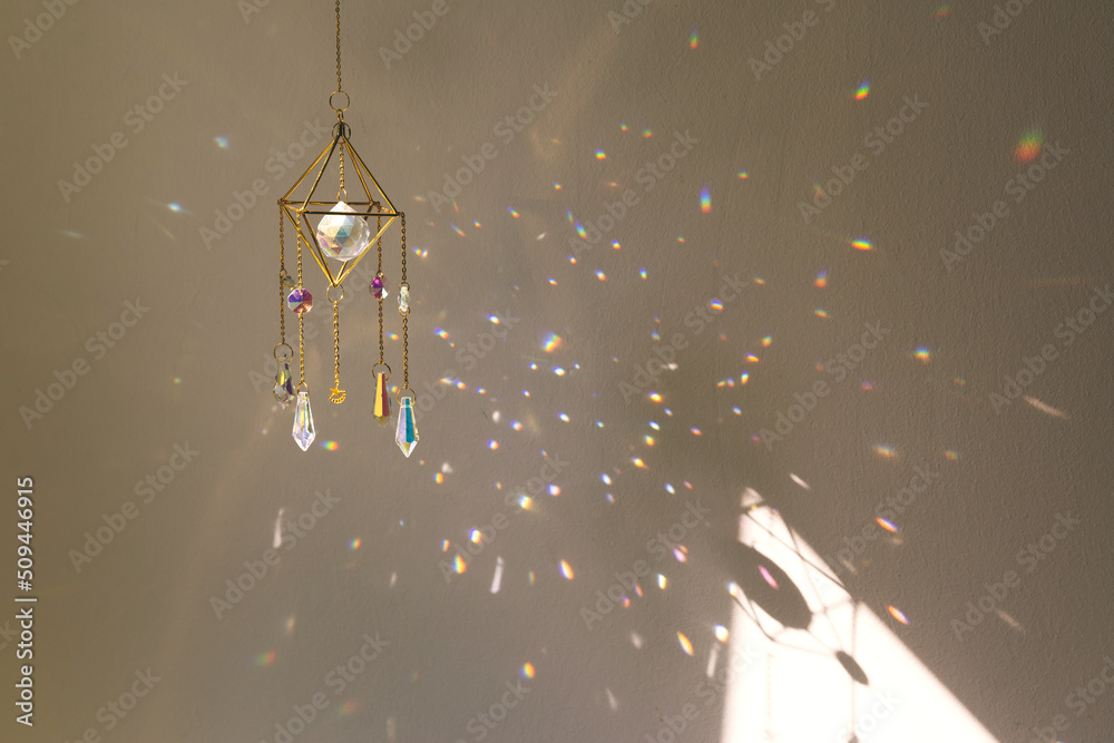 Suncatcher hanging in home during sunset. Many sun beams on the wall ...