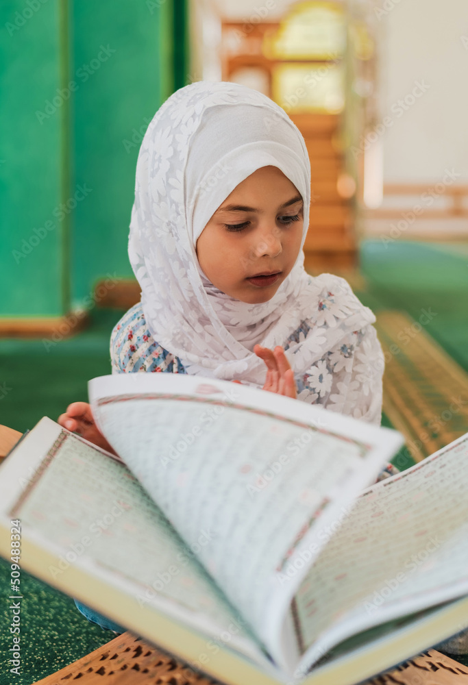Child girl reading a holy book Quran inside the mosque. Stock Photo ...
