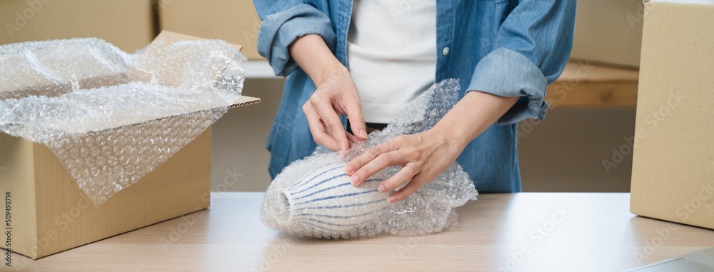 Young Asian woman owner of small online store packing customer orders ...