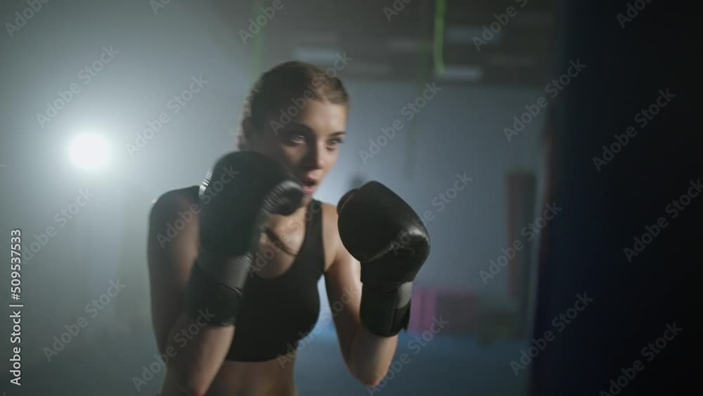 Woman power, female fighter beats a punching bag, trains his punches ...