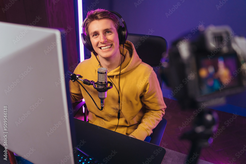 Happy young streamer pro gamer in headphones enjoying shooting vlog ...