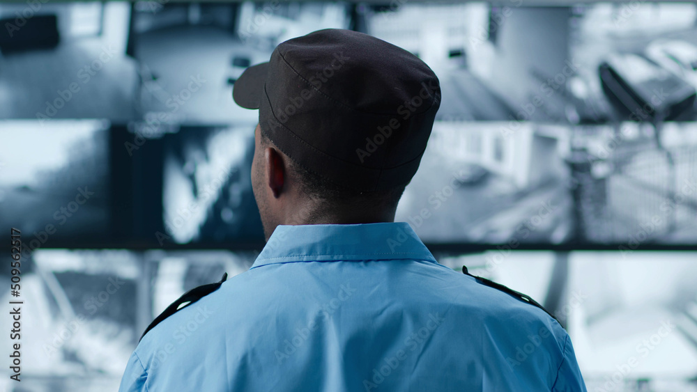 Back view of African-American security guard watching cctv screens in ...