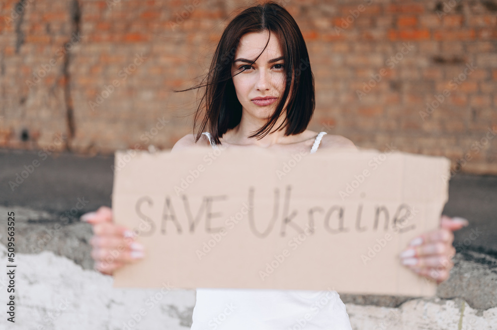 Portrait of a girl With a sign Save Ukraine, with a sad face. Girl in ...