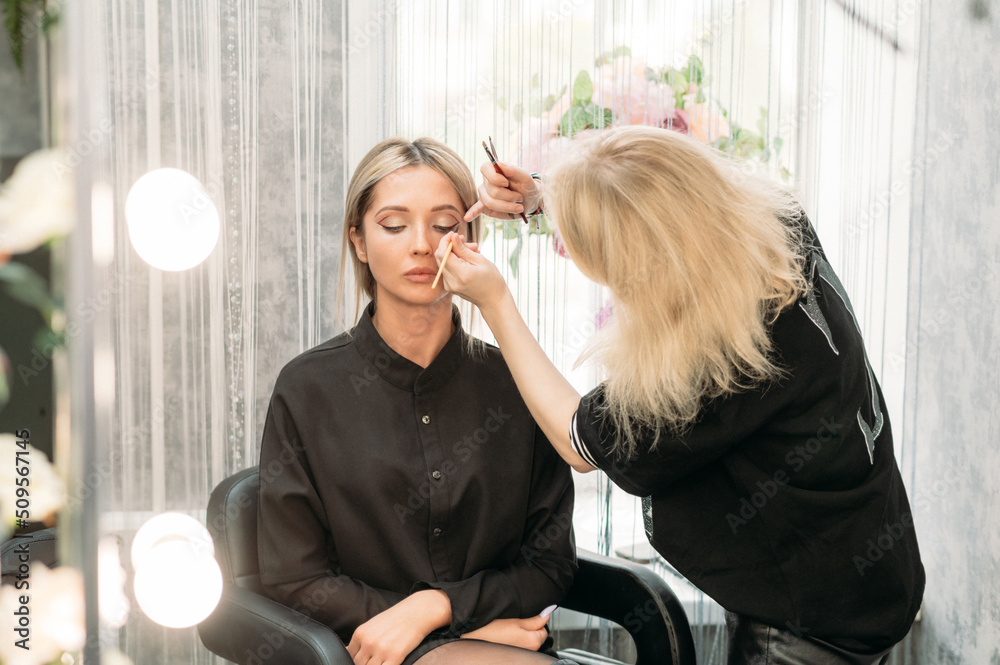 Shooting in a beauty salon. A young beautiful girl model master makeup ...