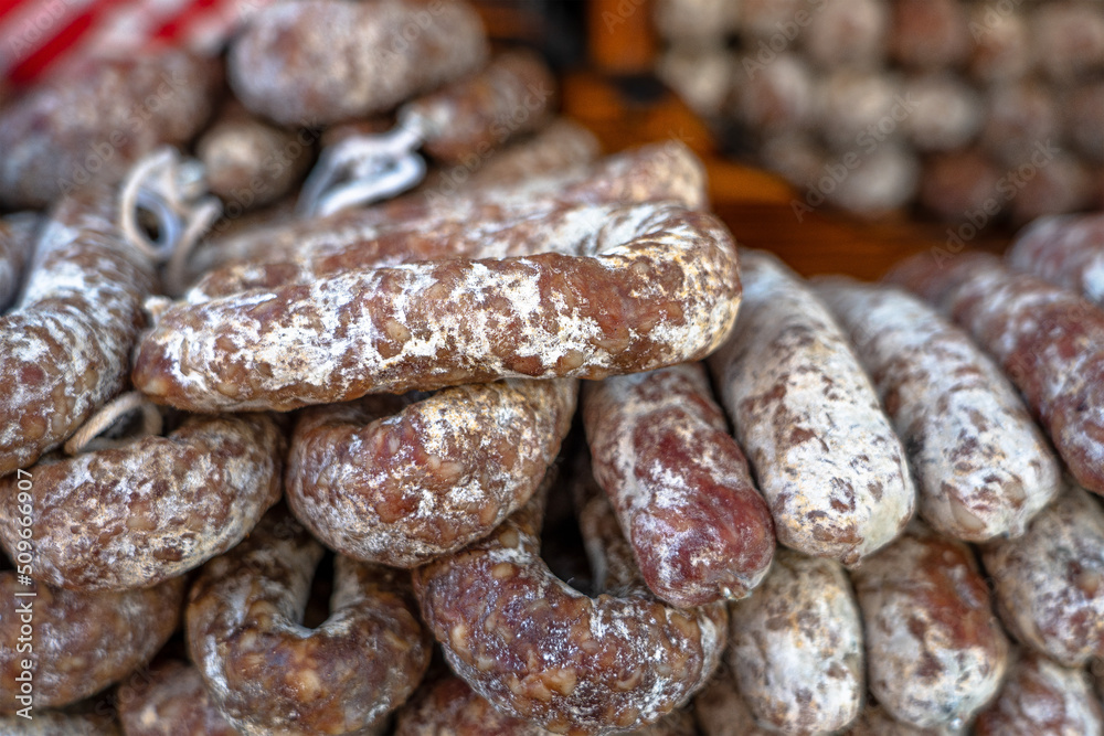Stacks of dry-cured sausages - saucisson, typically made of pork, or a ...