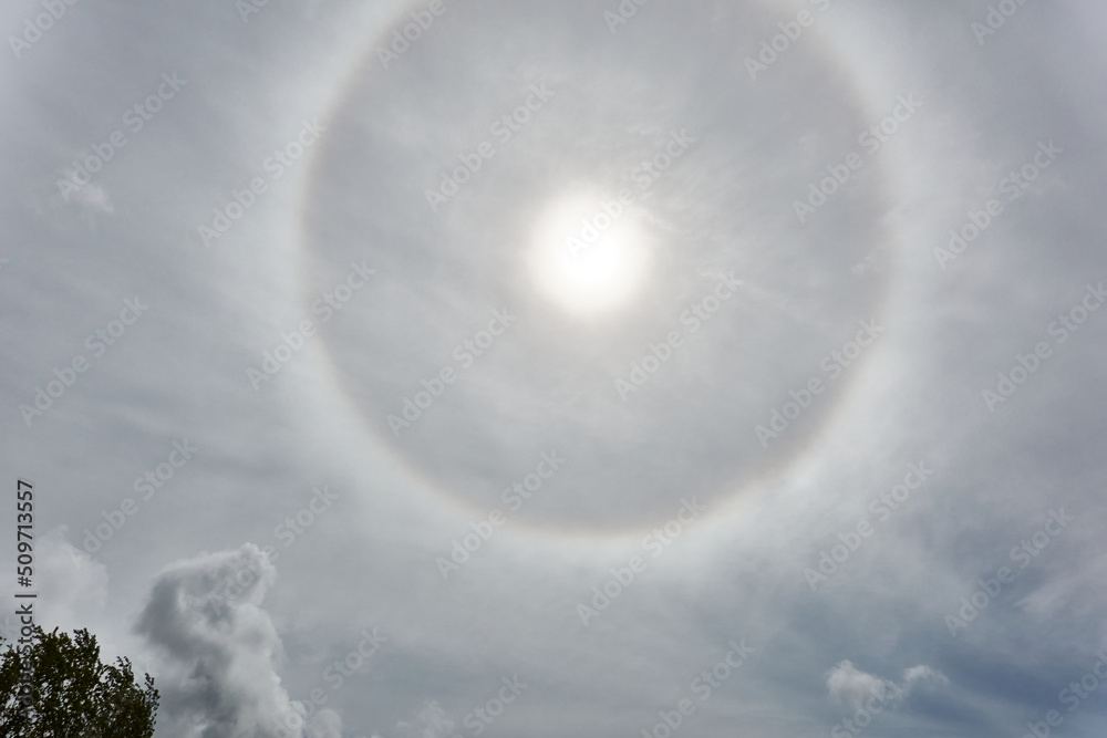 Round rainbow in a clear blue sky (sun halo), glowing cirrus and ...