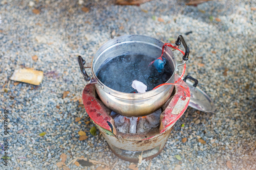Dyeing with natural color in a boiling pot on traditional clay stove ...