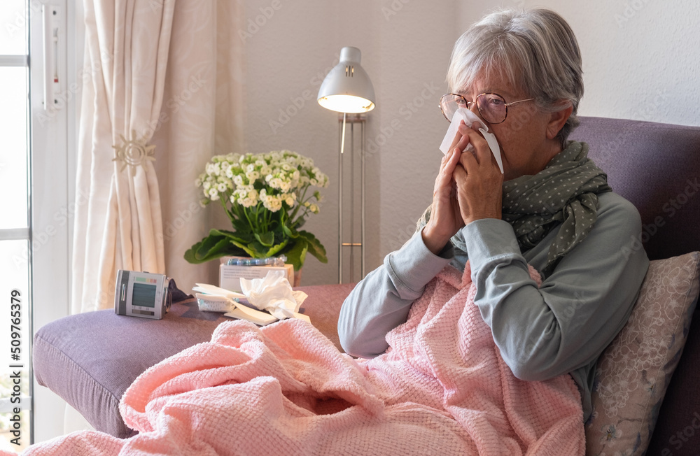 Older adult caucasian woman with severe cold and fever symptoms such as ...