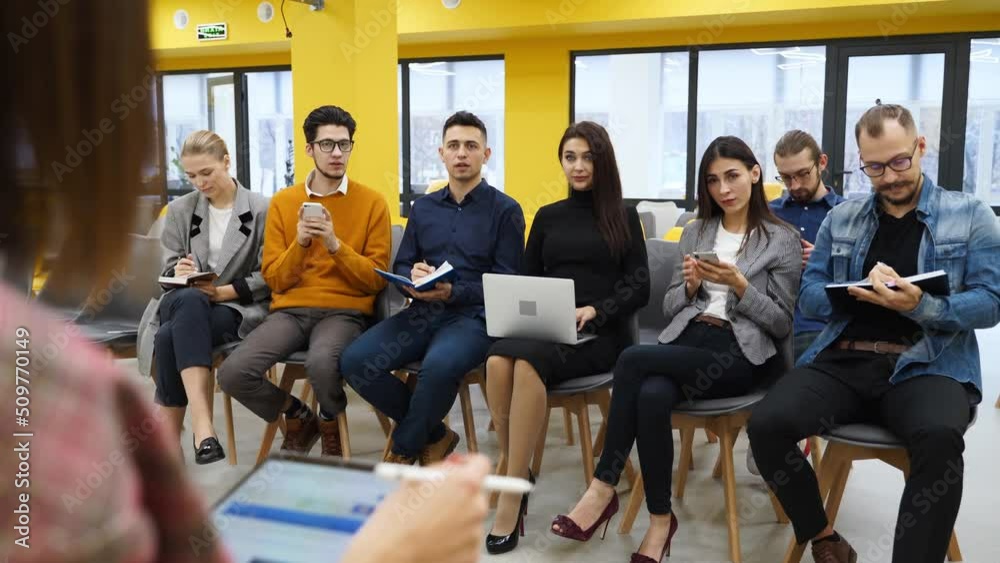 Listeners looking at presenter with tablet and diagrams on business ...