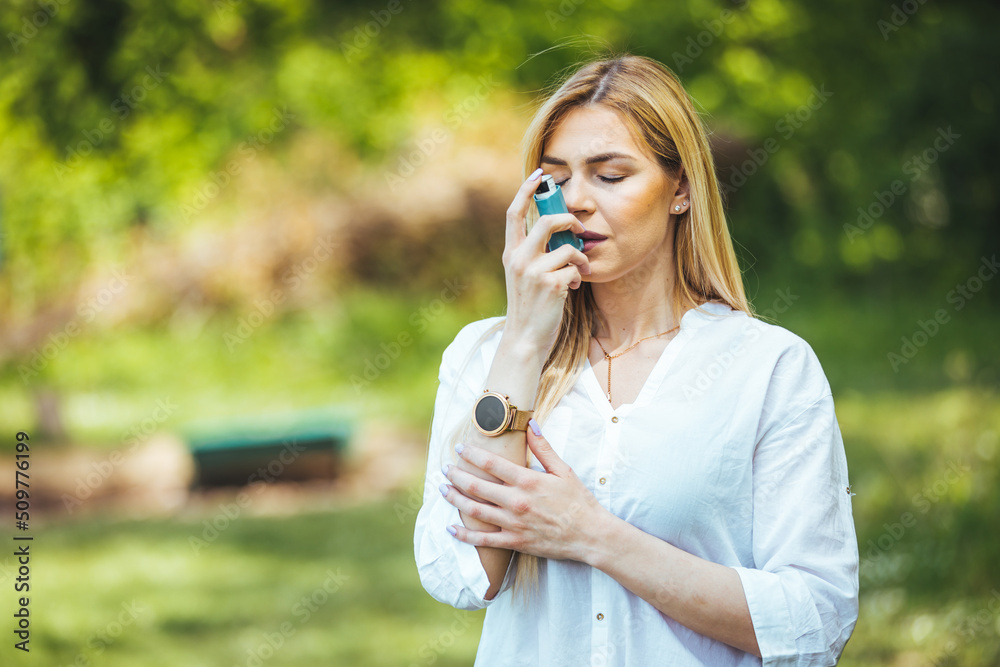 Woman using asthma inhaler in a park. Portrait of young handsome woman ...