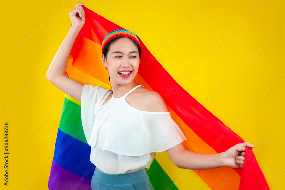 Happy asian woman with pride flag rainbow isolated yellow color ...