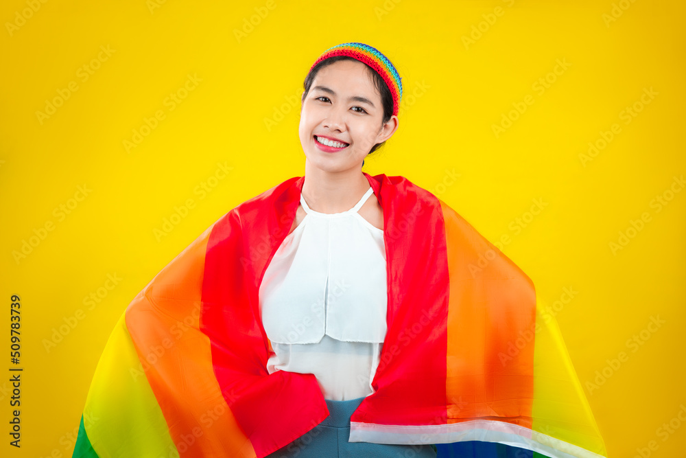 Happy asian woman with pride flag rainbow isolated yellow background ...