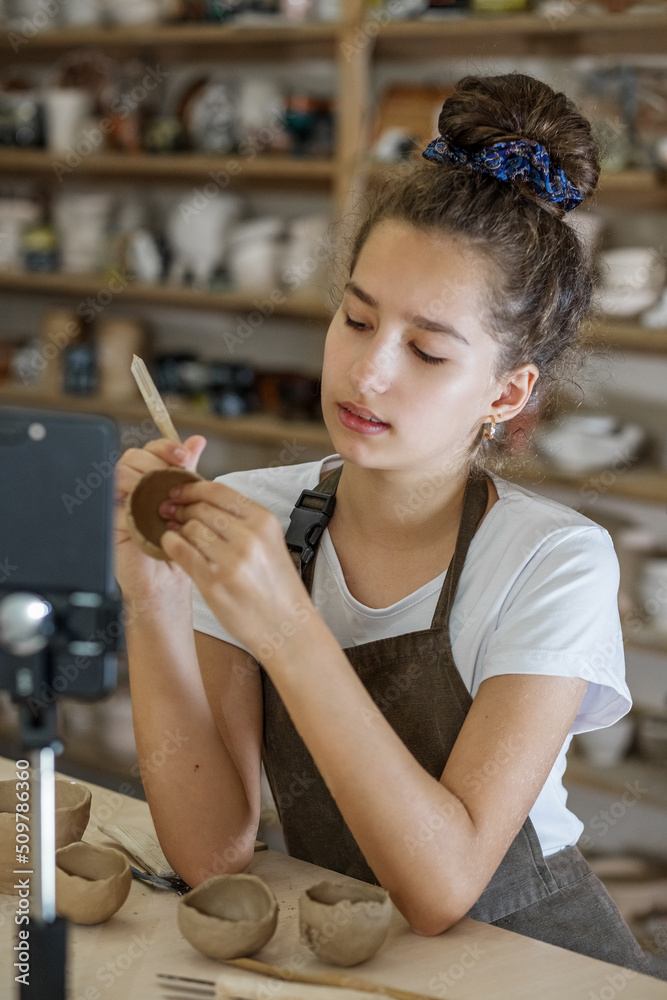 Beautiful teenage girl playing with modeling clay in pottery workshop ...
