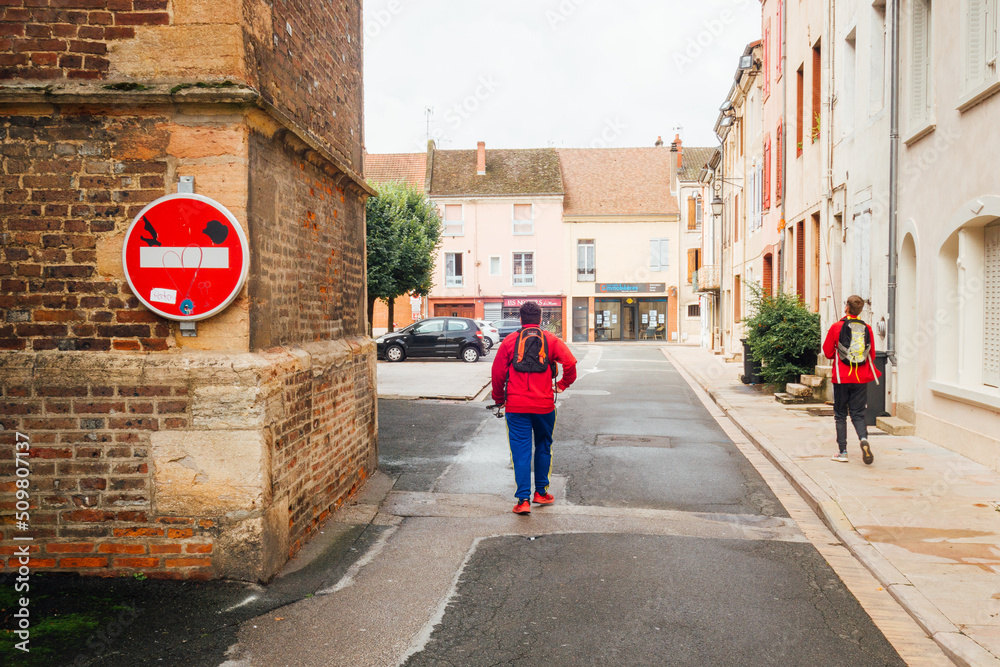 Des hommes en rouge marchant dans une rue. Un panneau sens interdit. La ...