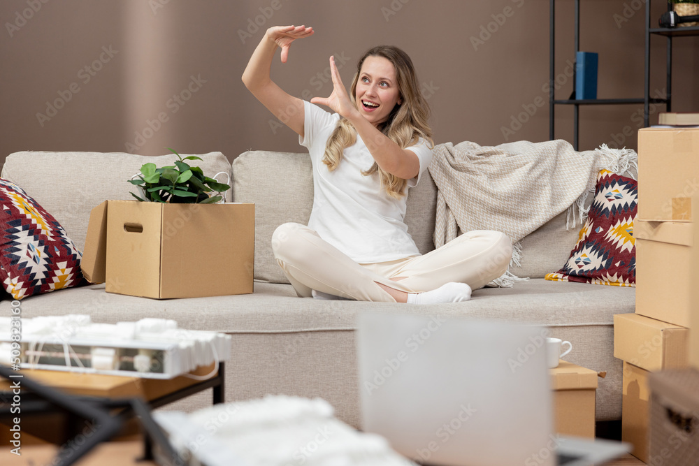 Cheerful happy woman is happy about moving into new apartment sits ...