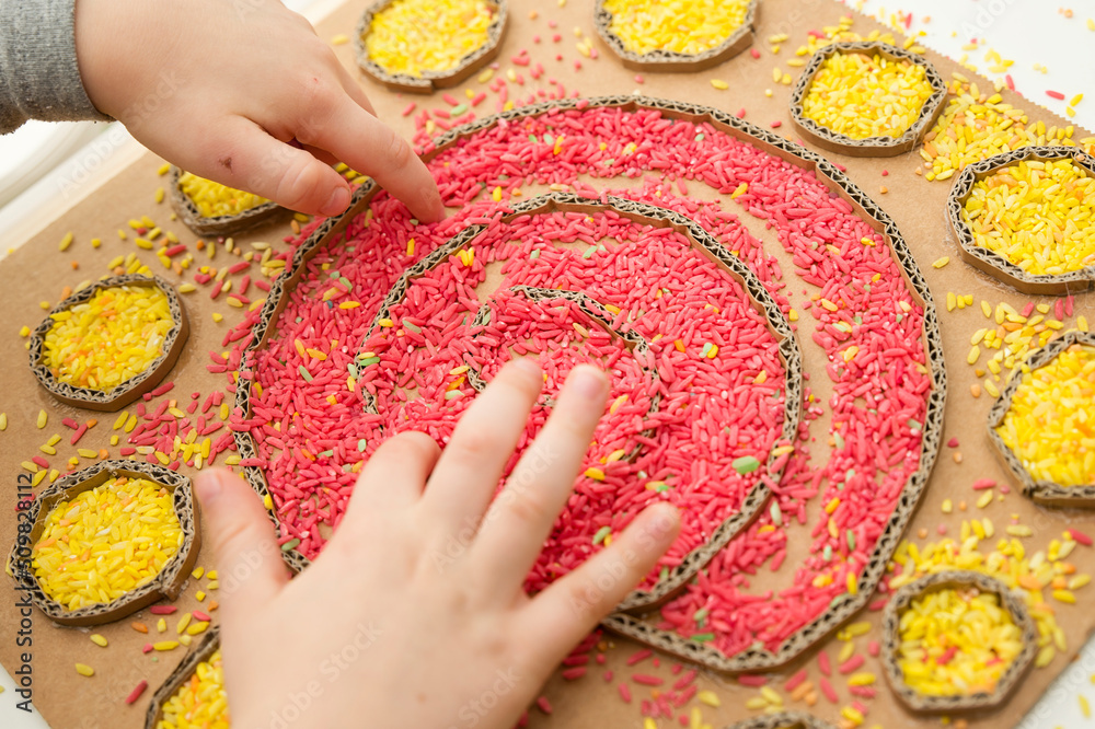 Boy plays with colored rice. Implement for children to develop fine ...