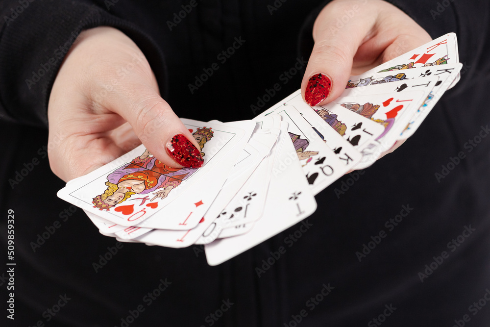 Female hands hold a deck of cards and show tricks. The photographer is ...