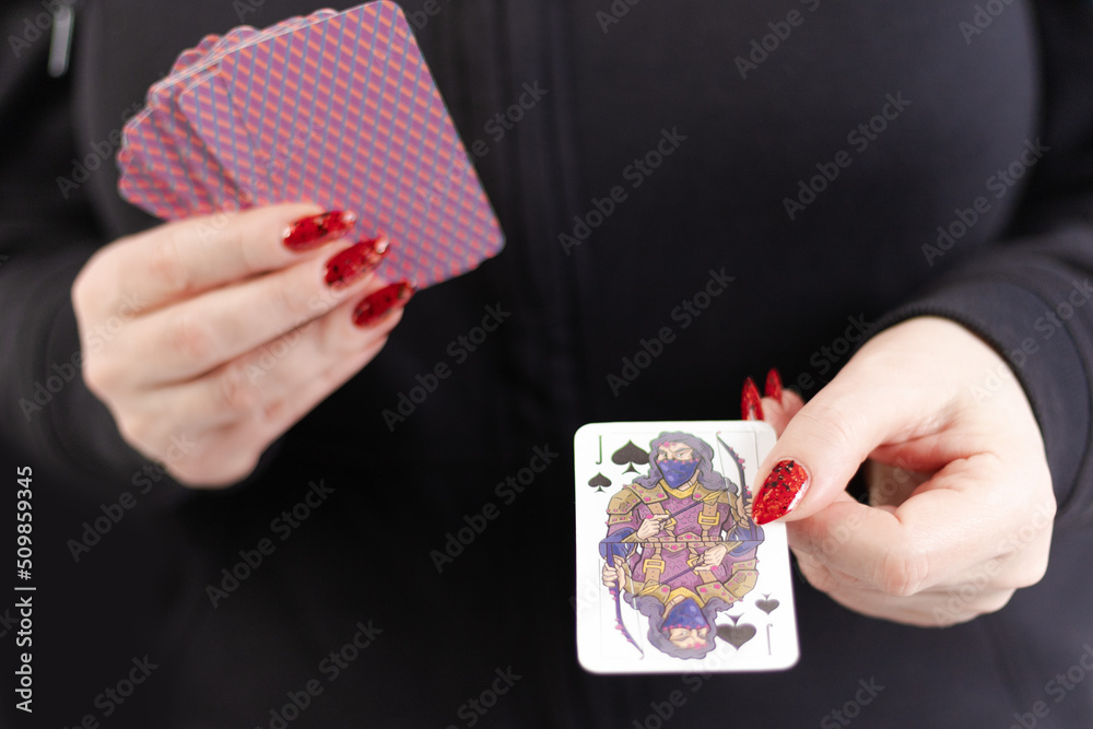 Female hands hold a deck of cards and show tricks. The photographer is ...