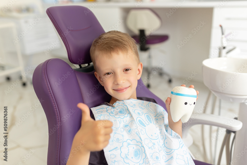 Dental clinic visit. Young positive boy patient showing thumbs up sign ...