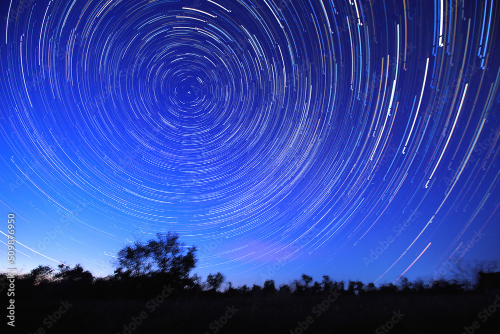 Star tracks in the sky. The movement of stars over a field and a lone ...