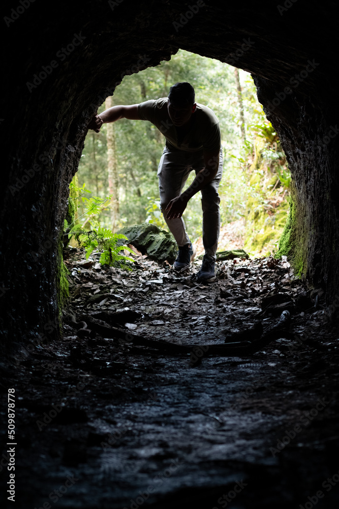 Silhouette of a person entering a small cave. Man exploring the ...
